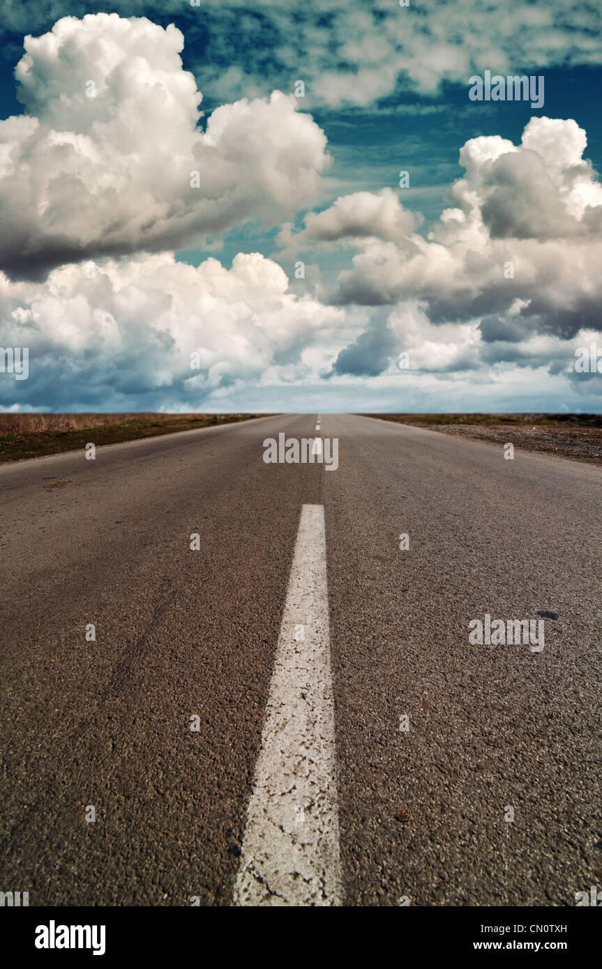 Beautiful sprig clouds over a highway road that stretches to infinity ...