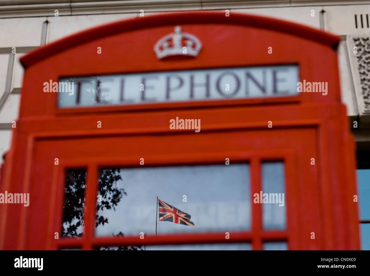 The Union Jack (UK flag) reflected in the window of a red phone booth ...