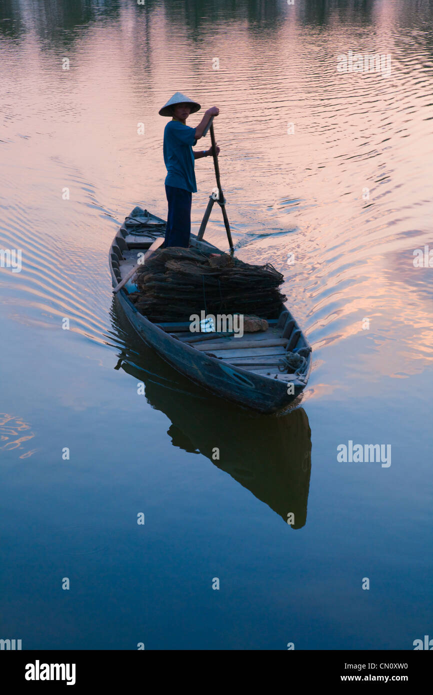 Girl with conical hat rowing boat on Thu Bon River at sunset, Hoi An ...