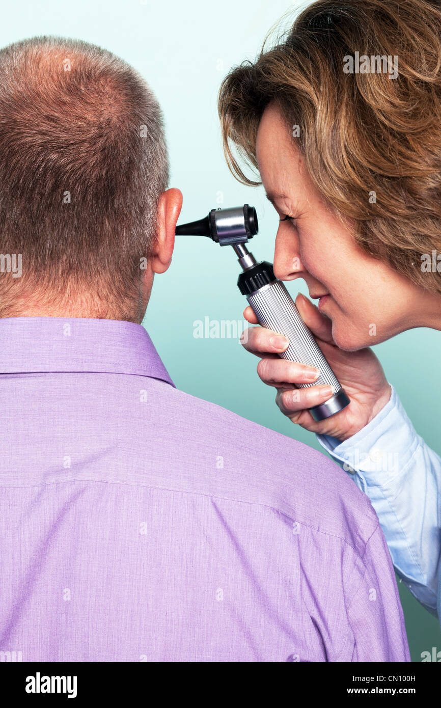 Photo of a female doctor examining a patients ear using an otoscope ...