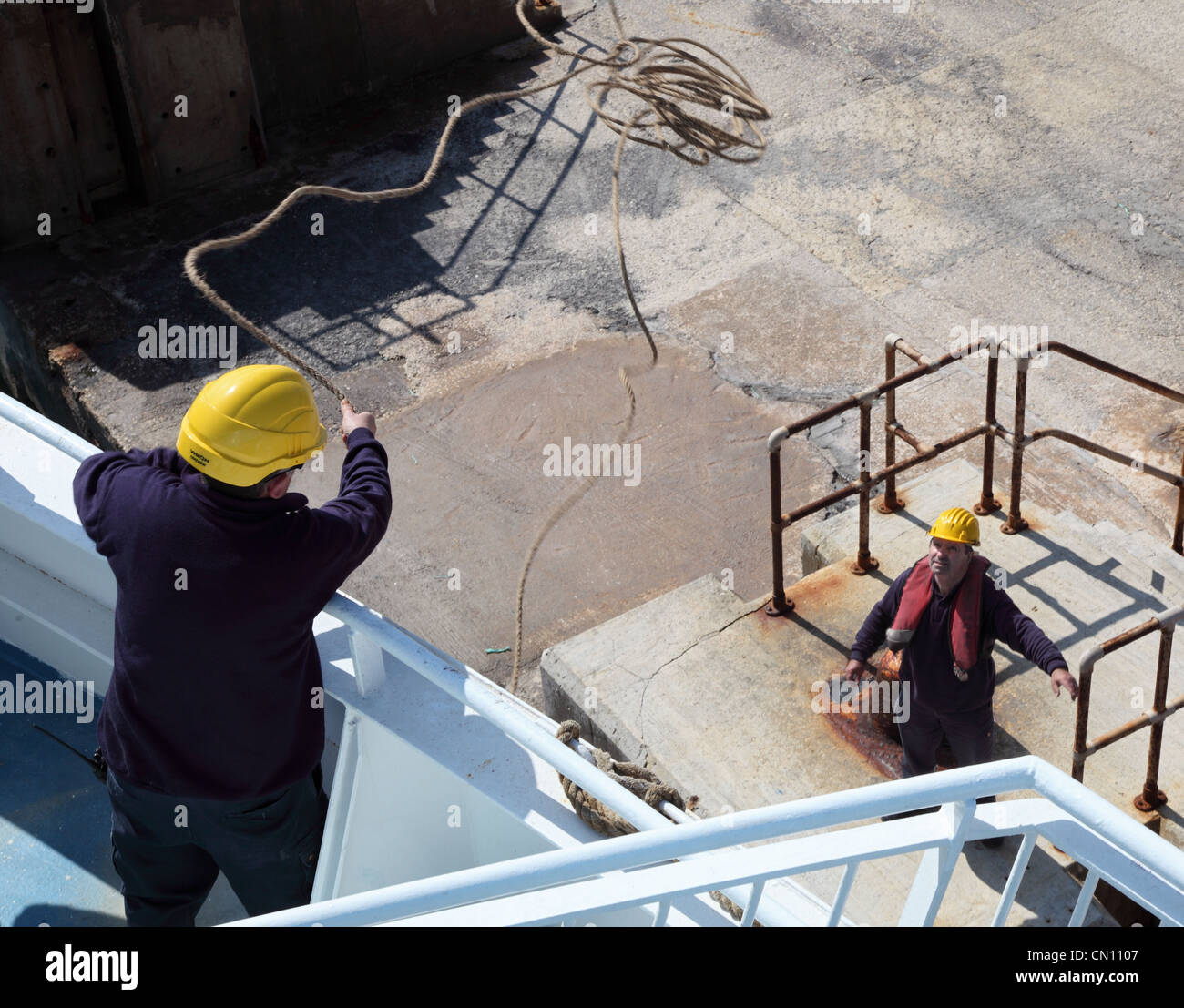 A deckhand on the Maltese ferry Malita throws a mooring rope to a ...
