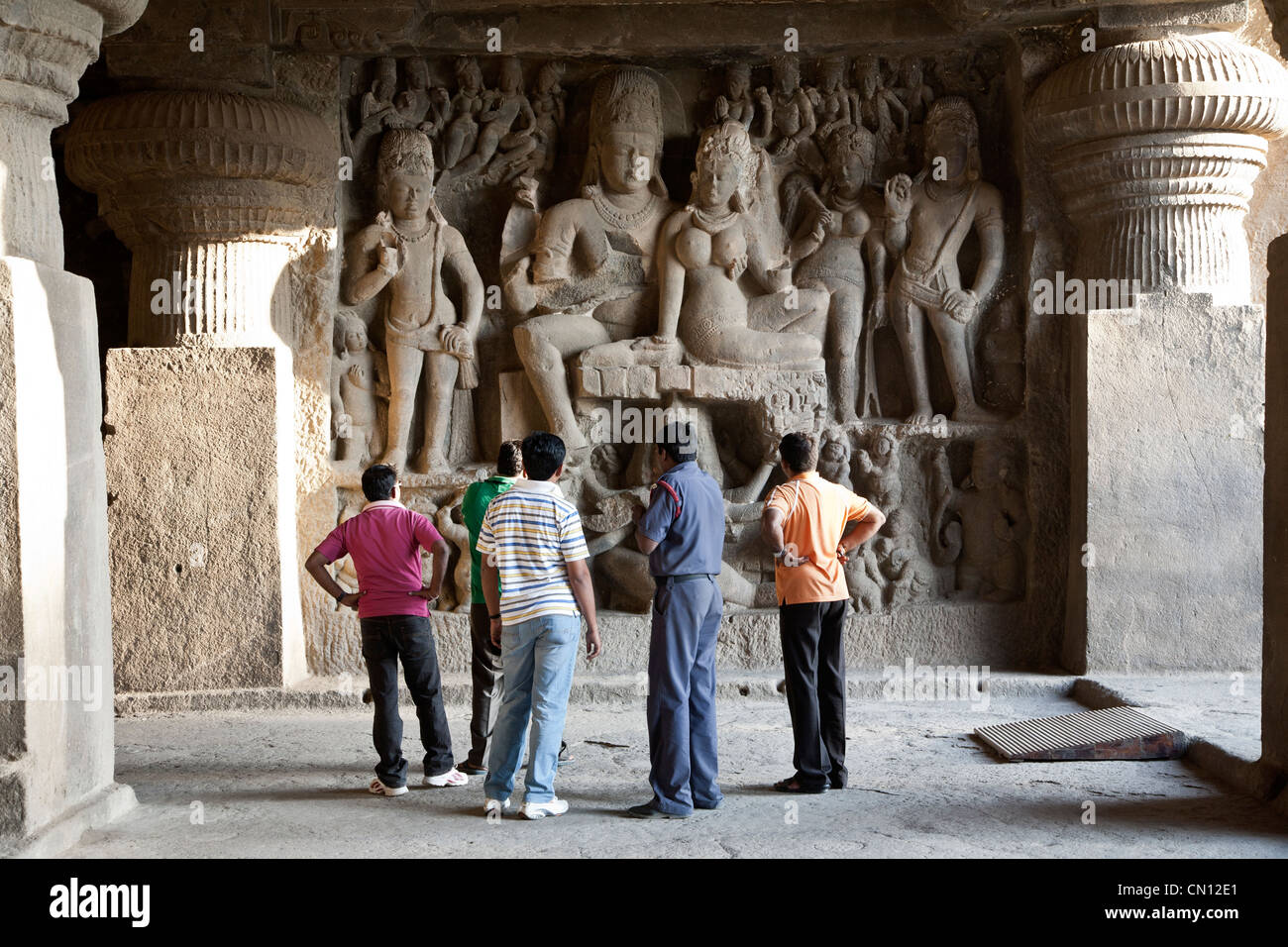 Indian tourists looking the stone carvings. Shiva and Parvati seated on ...