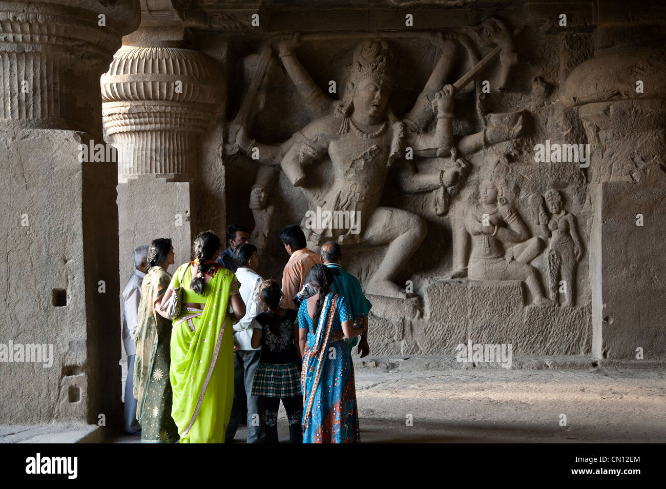 Indian tourists watching a stone carving depicting Shiva slaying the ...