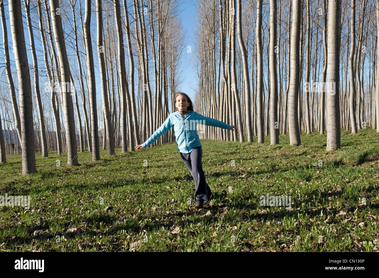 Young girl running among tall trees Stock Photo - Alamy