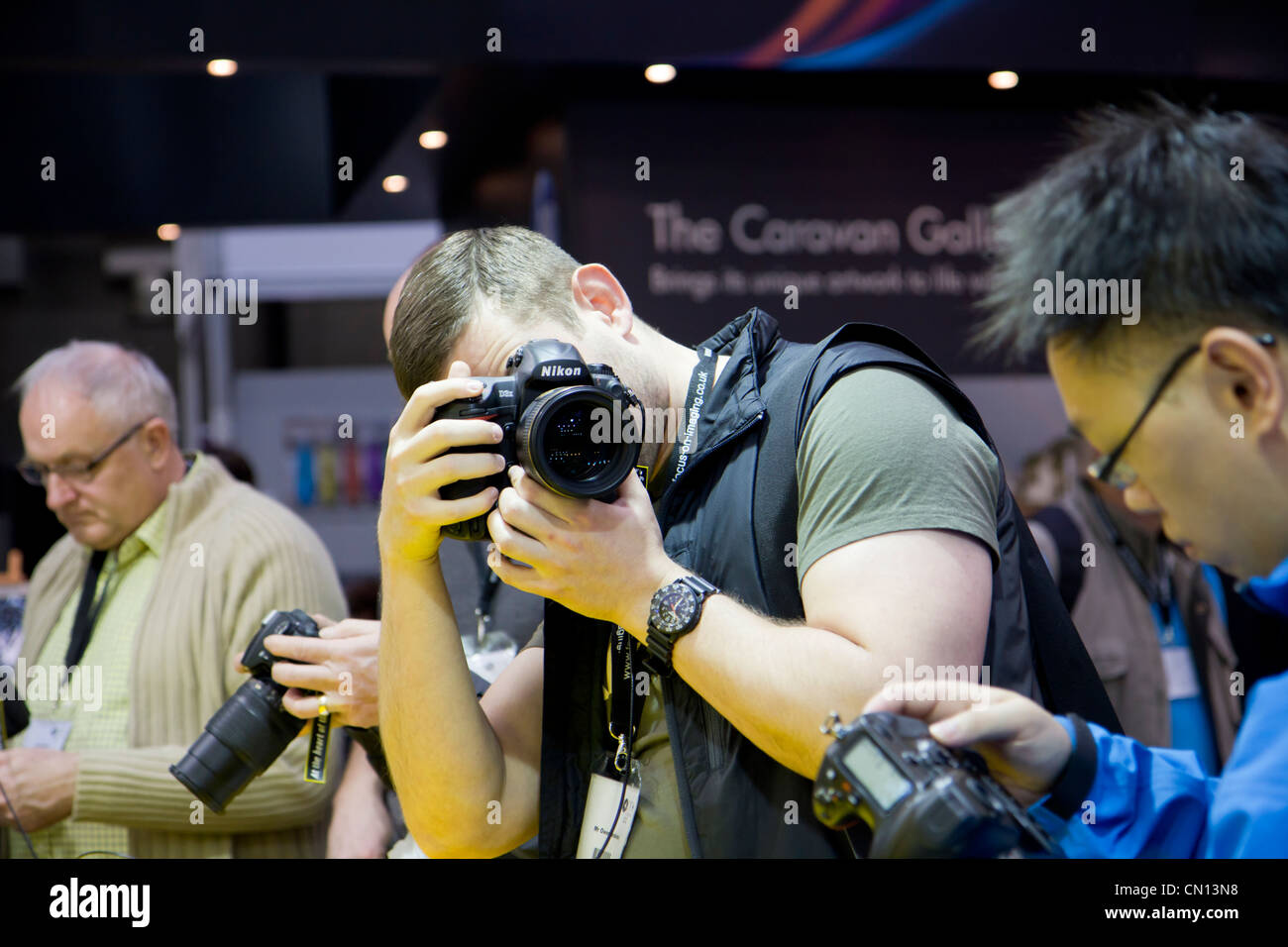 people trying out camera equipment at the Focus on imaging camera show ...