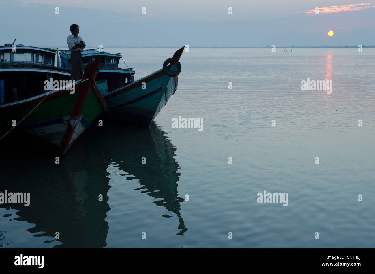 Man standing on his boat at sunrise in Labutta harbour. Irrawaddy delta ...