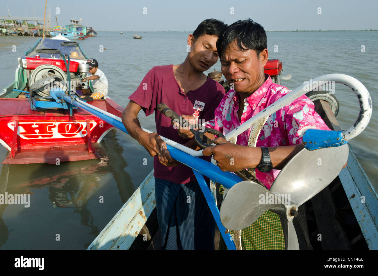 2 men fixing their boat propeller. Labutta harbour. Irrawaddy delta ...