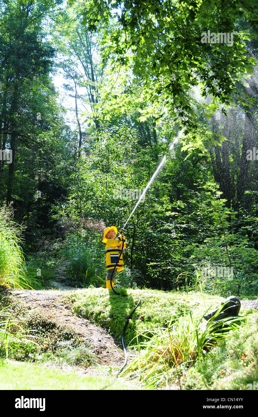 Little boy dressed as a fireman spraying water into trees, Simcoe ...