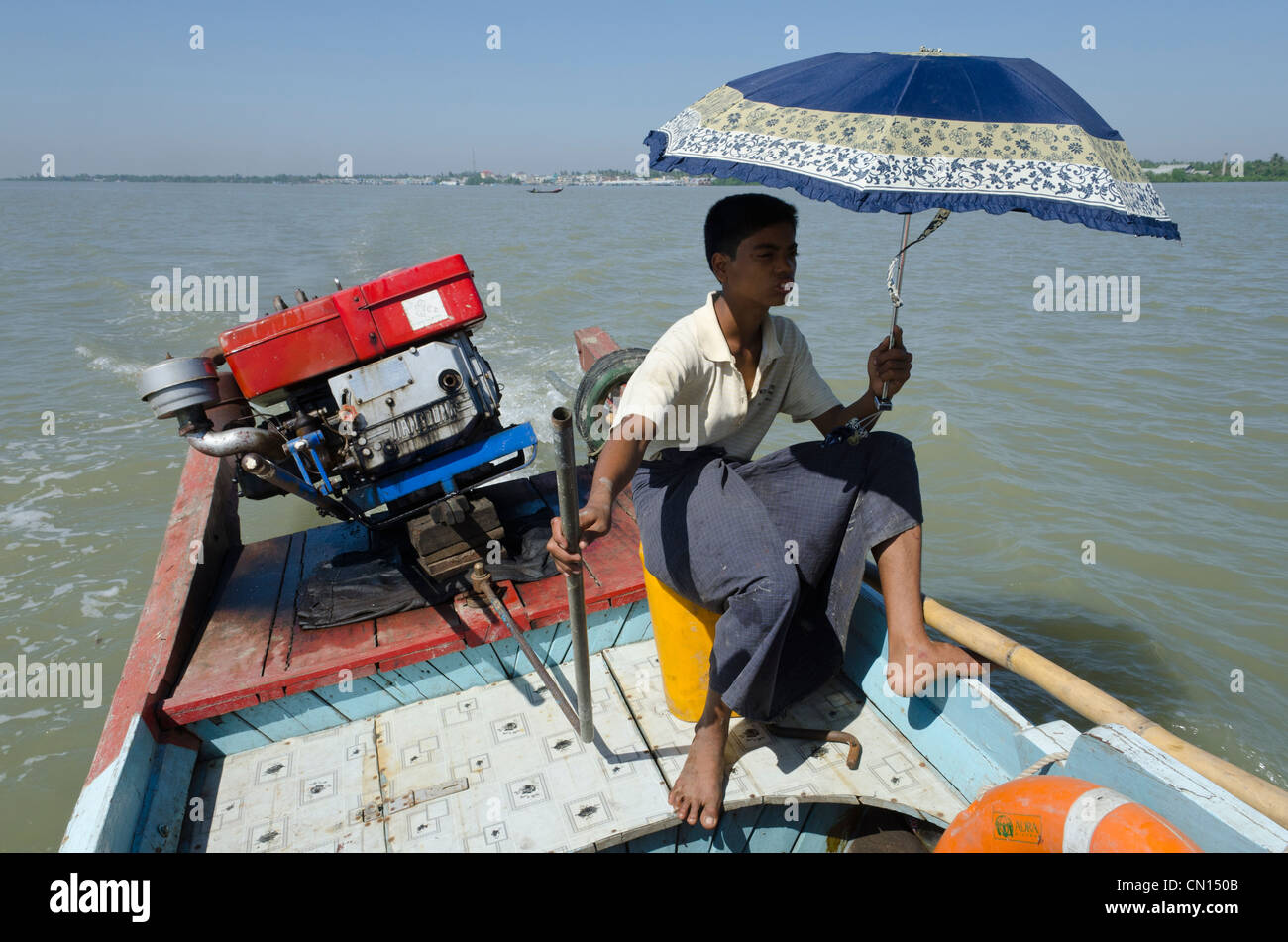 Boy with umbrella driving his outboard boat. Labutta. Irrawaddy delta ...
