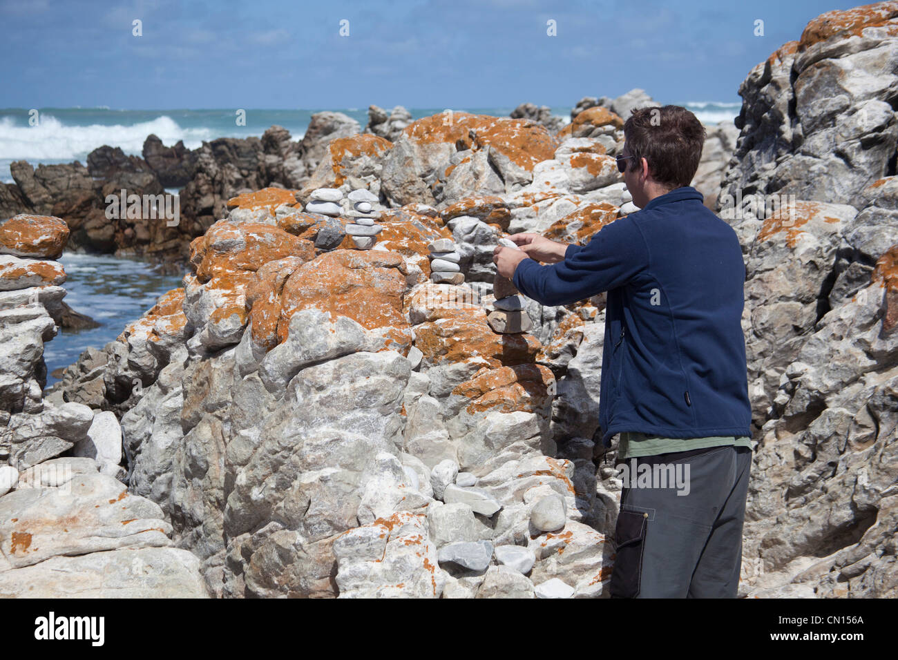 A man taking a picture of the rocks at Cape L'Agulhas, South Africa ...