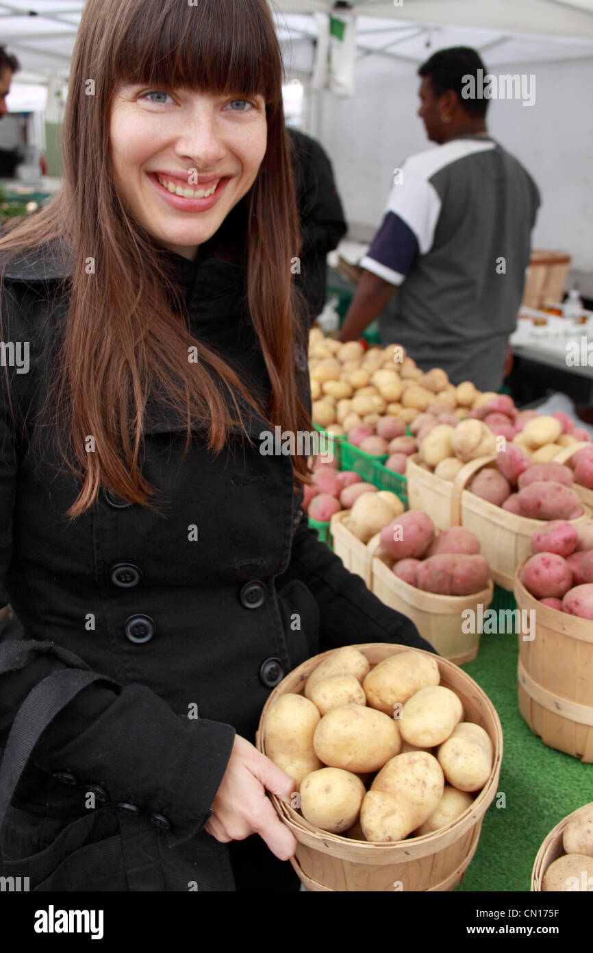 Woman at a local farmers market holding potatoes, Toronto, Ontario ...
