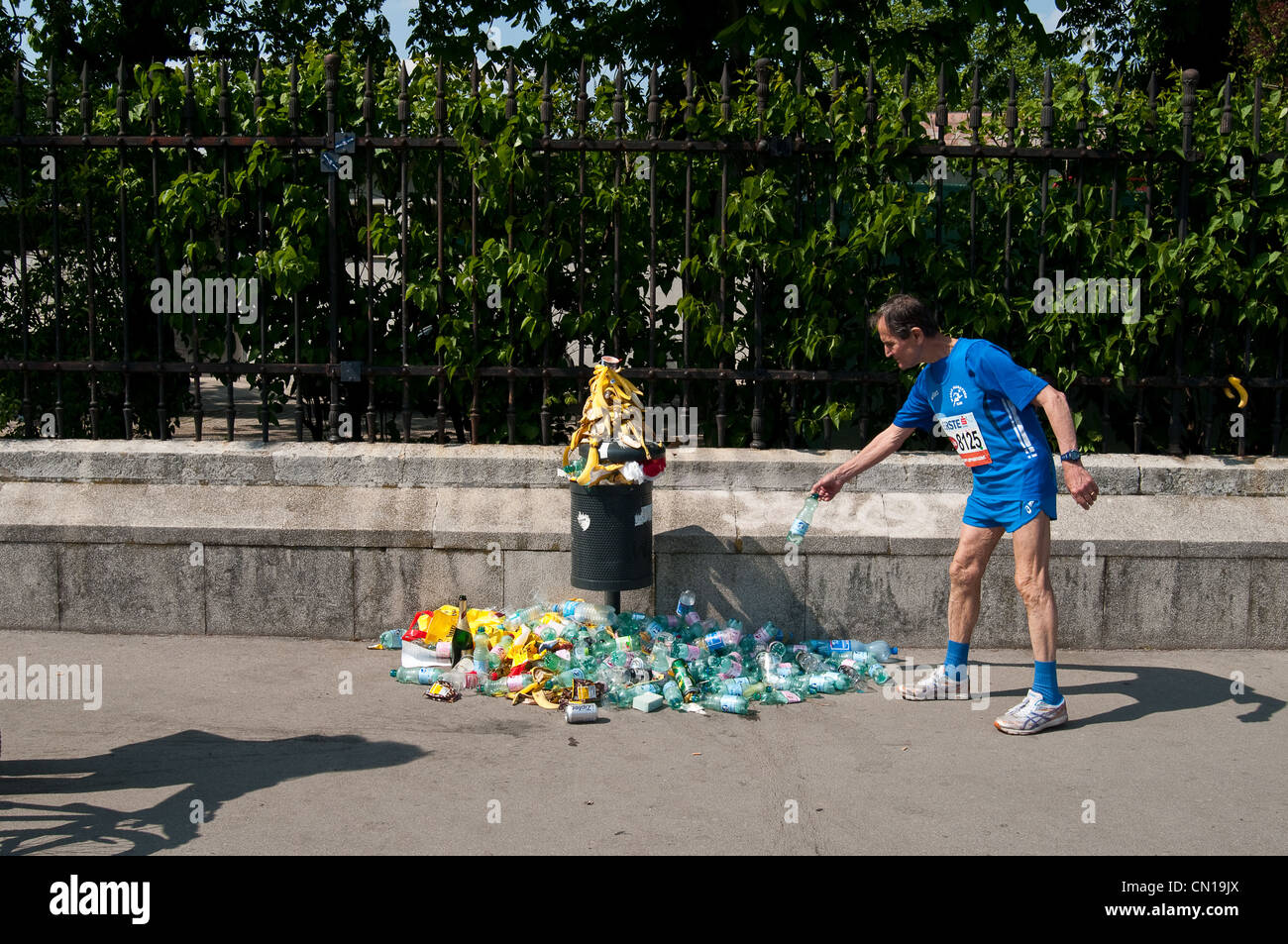 A marathon runner attempts to add an empty bottle to a pile of rubbish ...