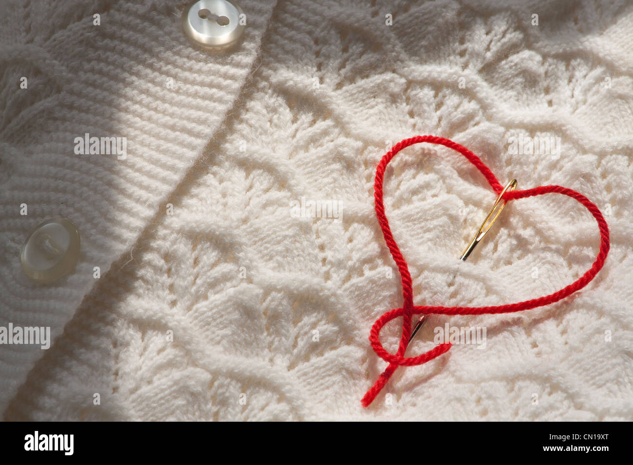 Needle with red thread in the shape of a heart stuck in a woman's ...