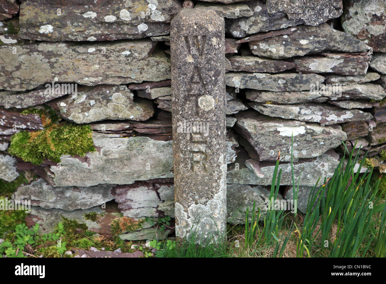 Stone water marker against a dry stone wall Stock Photo - Alamy