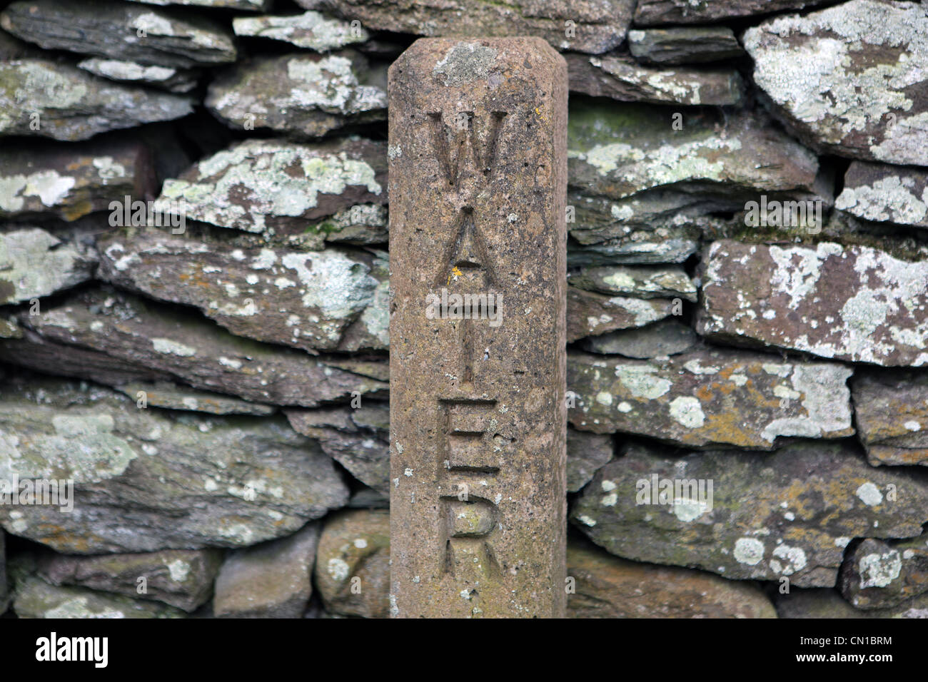 Stone water marker against a dry stone wall Stock Photo - Alamy