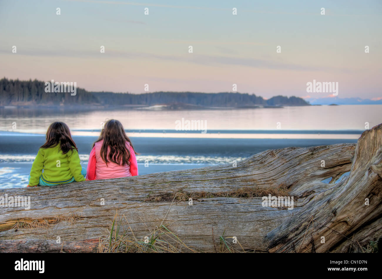 Young First Nation girls sitting on a log, Vancouver Island, British ...