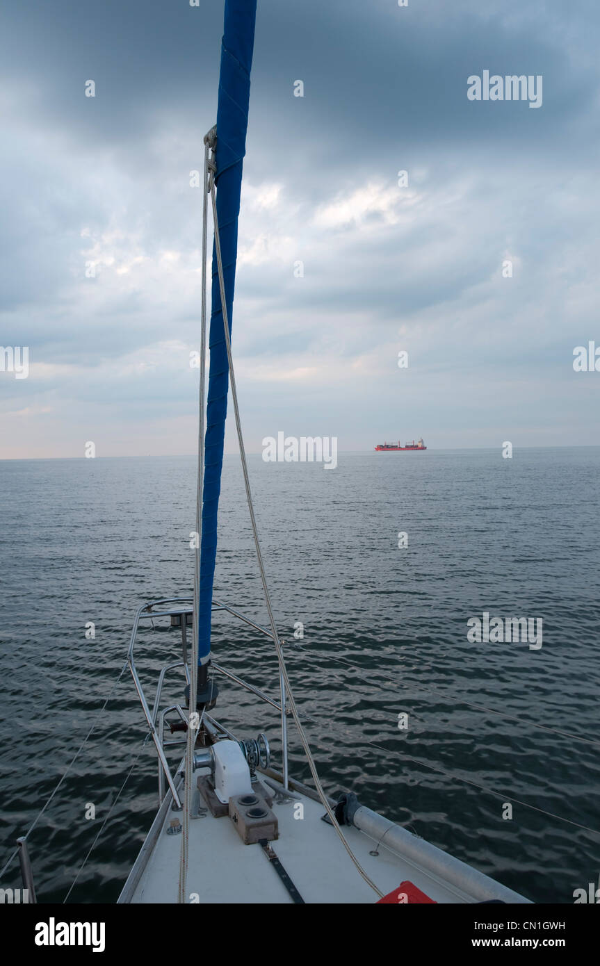 Front of Sailboat at Sea With Freight Ship in Background Stock Photo ...