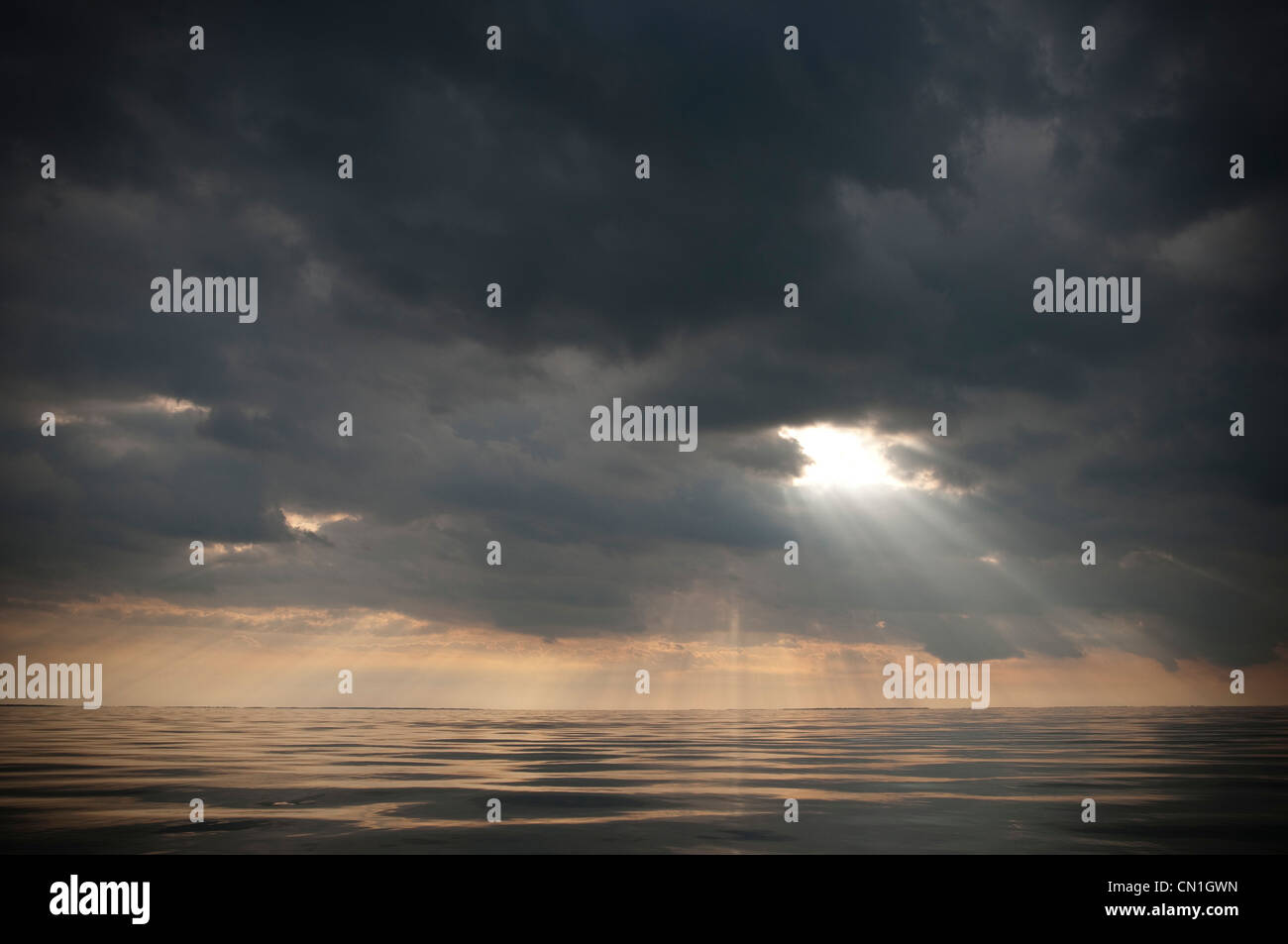 Sunlight Filtering Dramatic Gray Clouds Over Water Stock Photo - Alamy