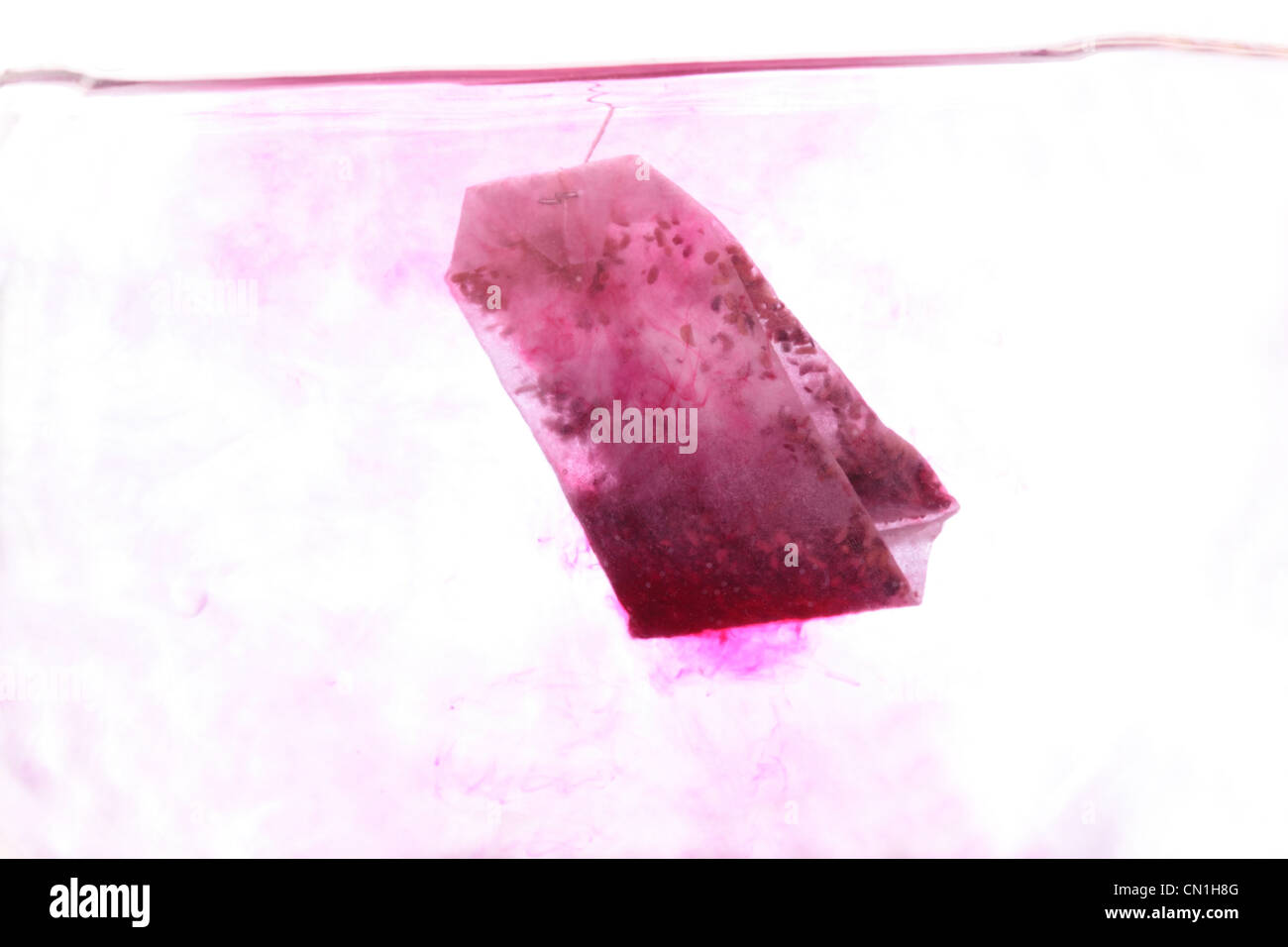 red Teabag in hot water in white background Stock Photo - Alamy
