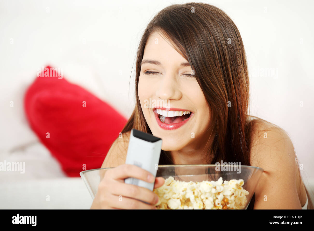 Girl watching TV having fun eating popcorn Stock Photo - Alamy