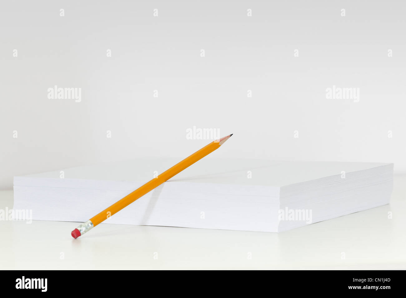 Pencil Leaning Against Stack of White Paper Stock Photo - Alamy