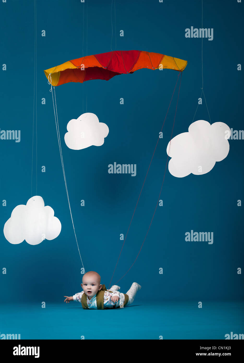 Little baby with the parachute on blue background Stock Photo - Alamy