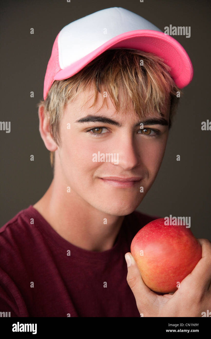 Young caucasian in a cap, holding apple looking at camera Stock Photo ...