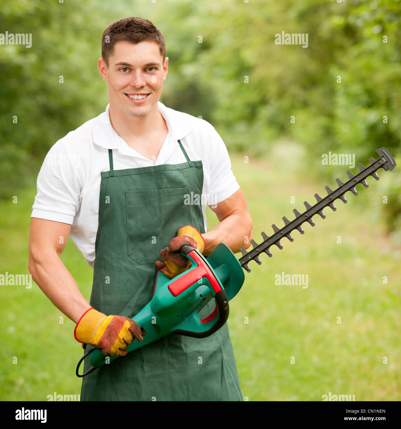 Young and smiling gardener with hedge cutter Stock Photo - Alamy