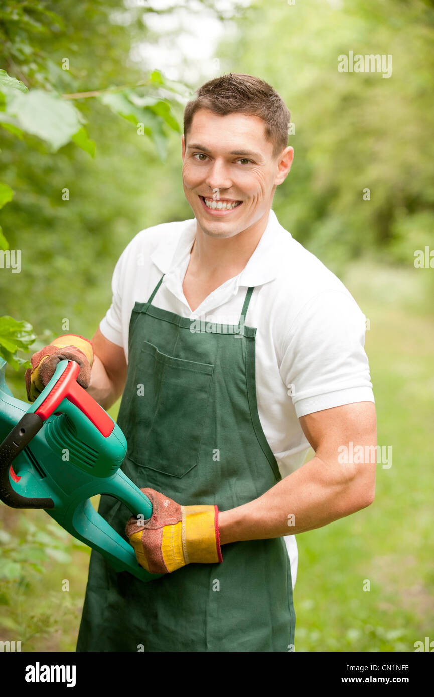Young and smiling gardener with hedge cutter Stock Photo - Alamy