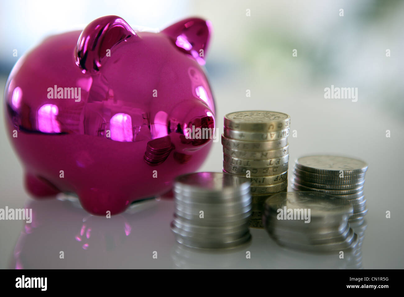 Pink piggy bank and piles of money Stock Photo - Alamy
