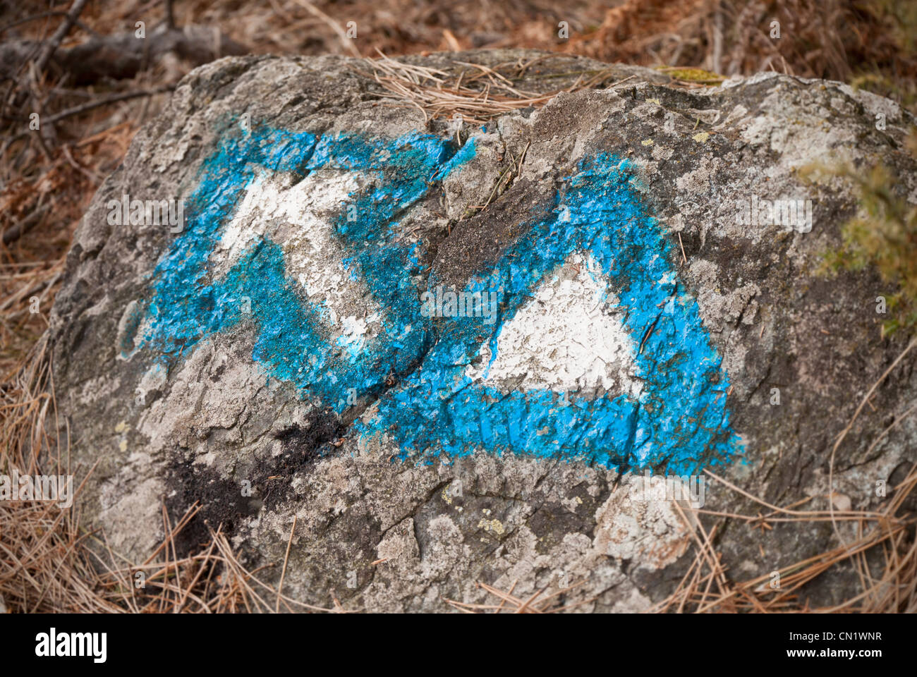 Hiking signs, arrow and triangle, painted in blue and white on a rock ...