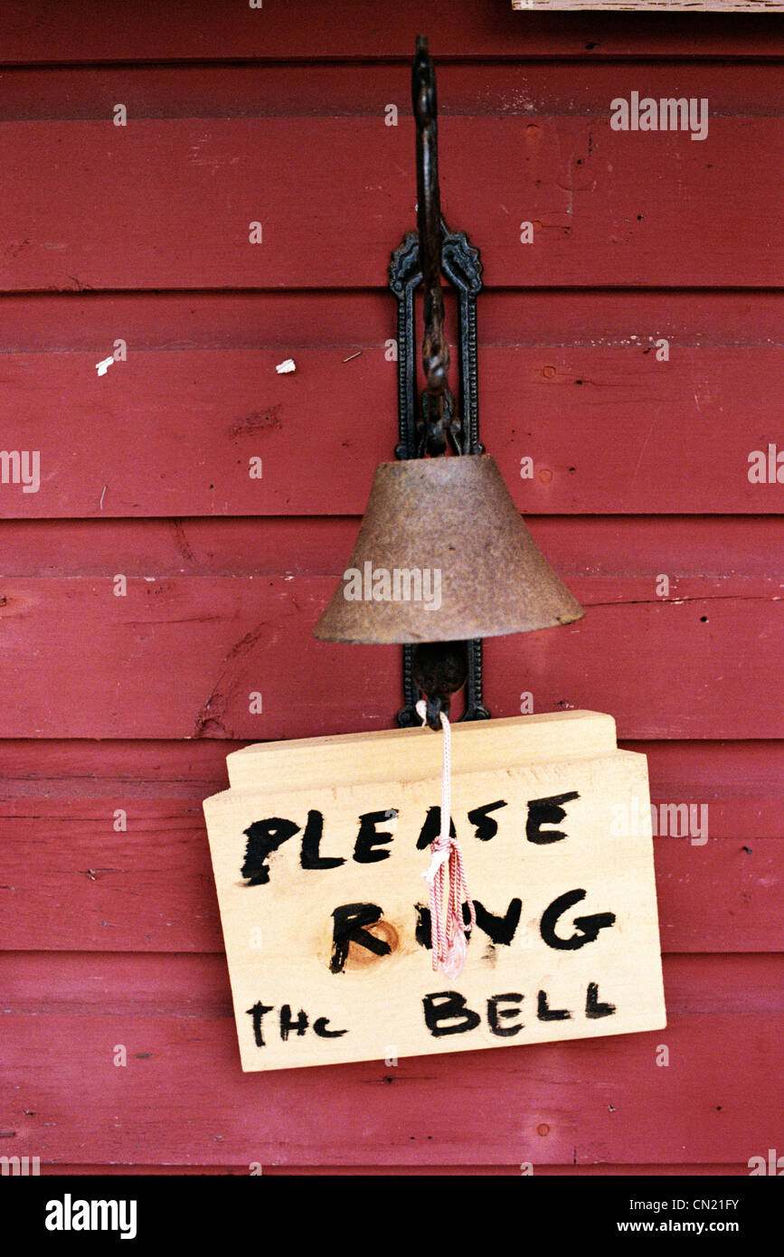 Metal bell and sign saying please ring the bell Stock Photo - Alamy