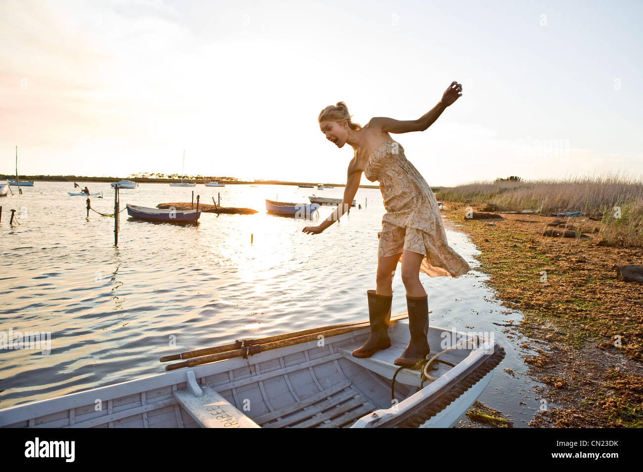 Smiling Young Woman in Gum Boots Balancing on Boat Stock Photo - Alamy