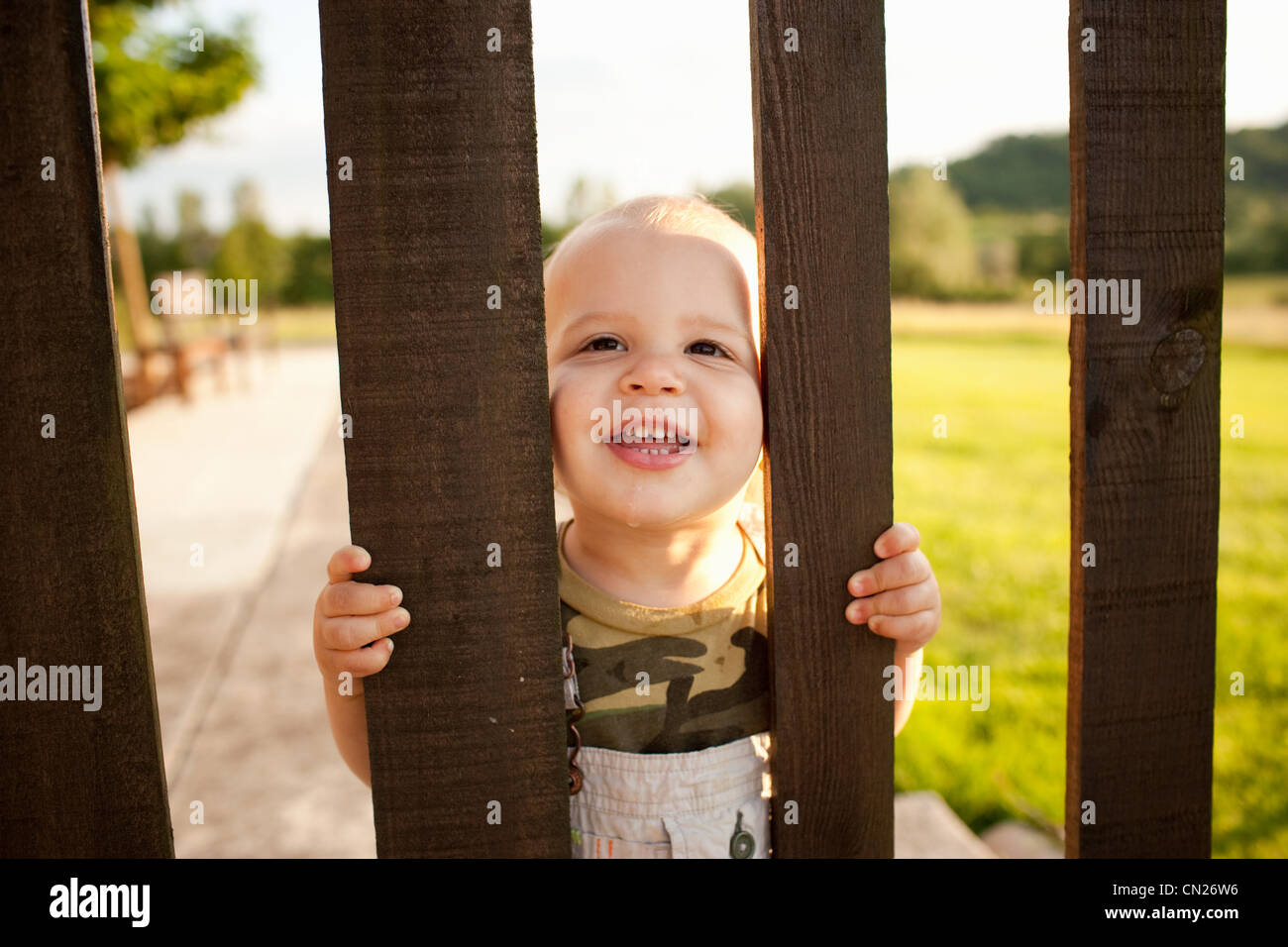 Toddler looking through wooden gate Stock Photo - Alamy