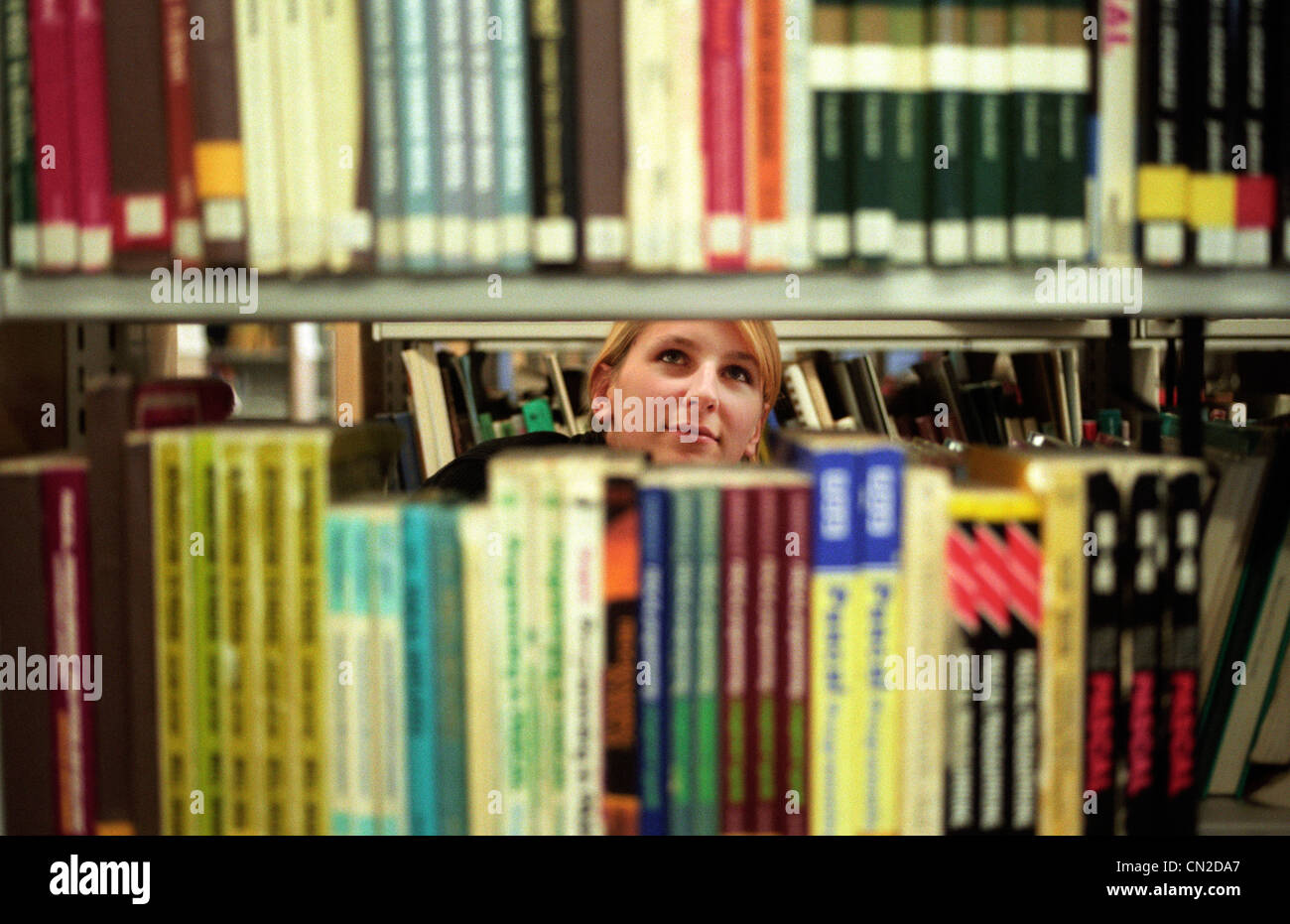 A female undergraduate searches through reference books in a library in ...