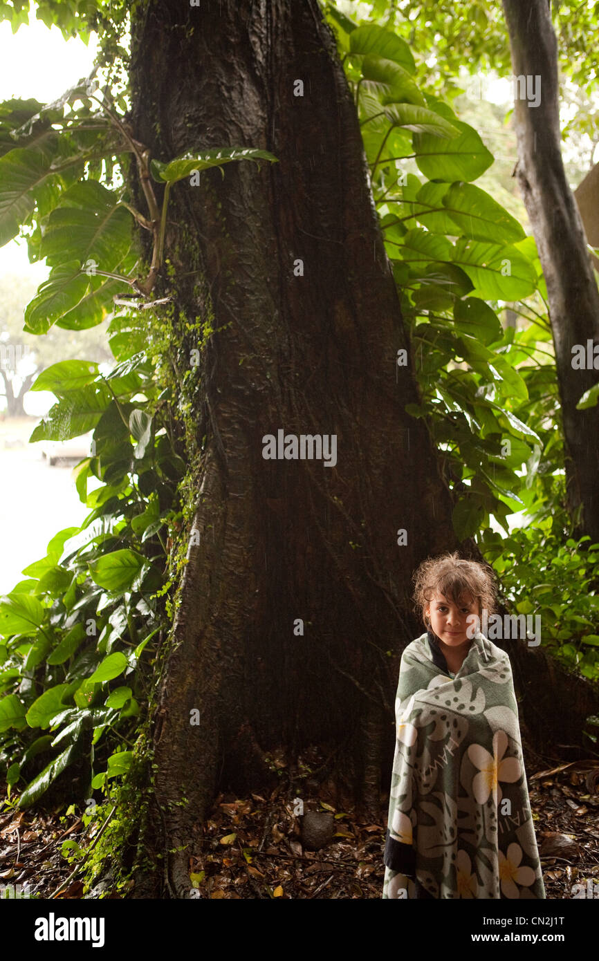 Young girl standing by tree Stock Photo - Alamy