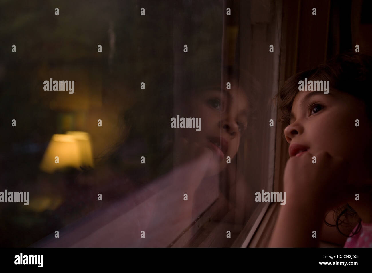 Young girl looking through window Stock Photo - Alamy