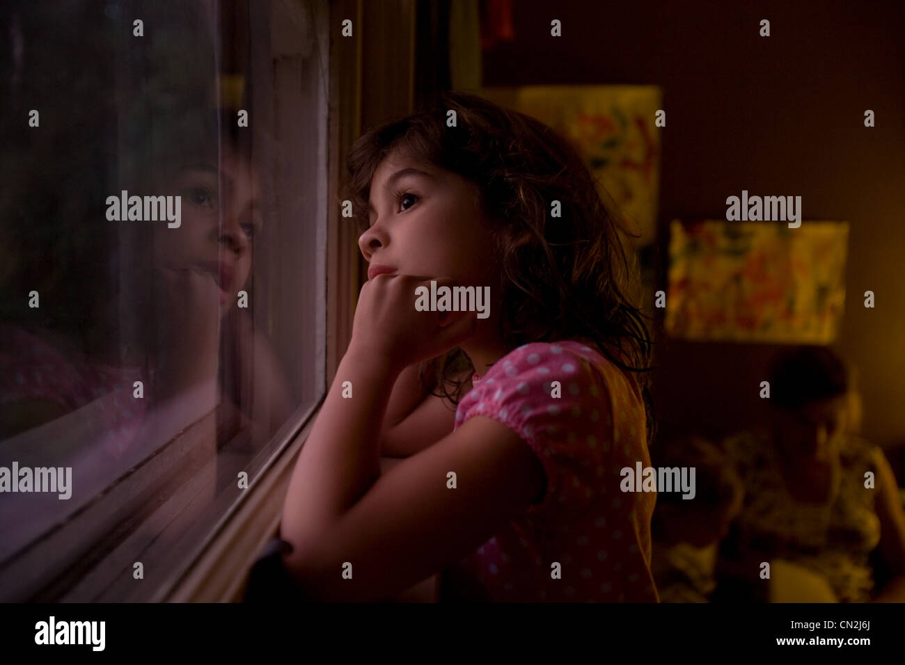 Young girl looking through window Stock Photo - Alamy