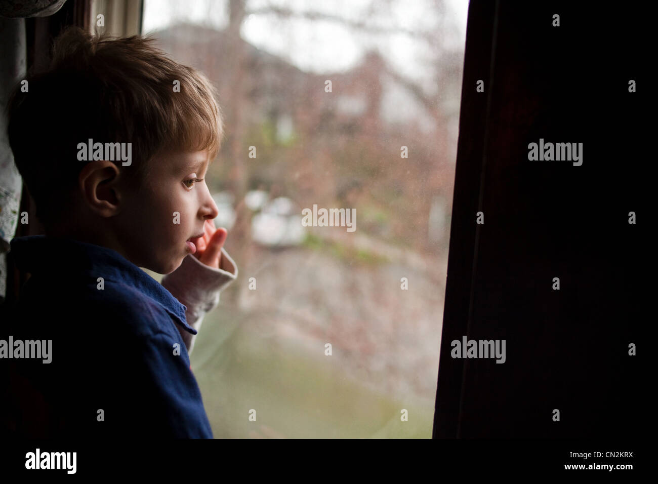 Young boy looking through window Stock Photo - Alamy
