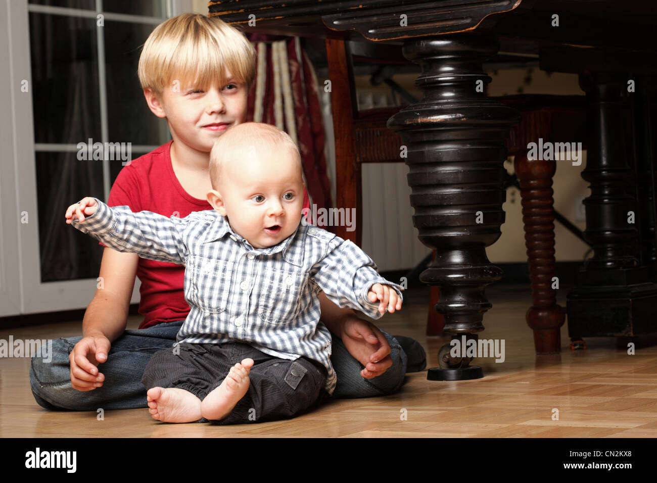 Blond boy with his newborn baby brother indoor, children playing Stock ...