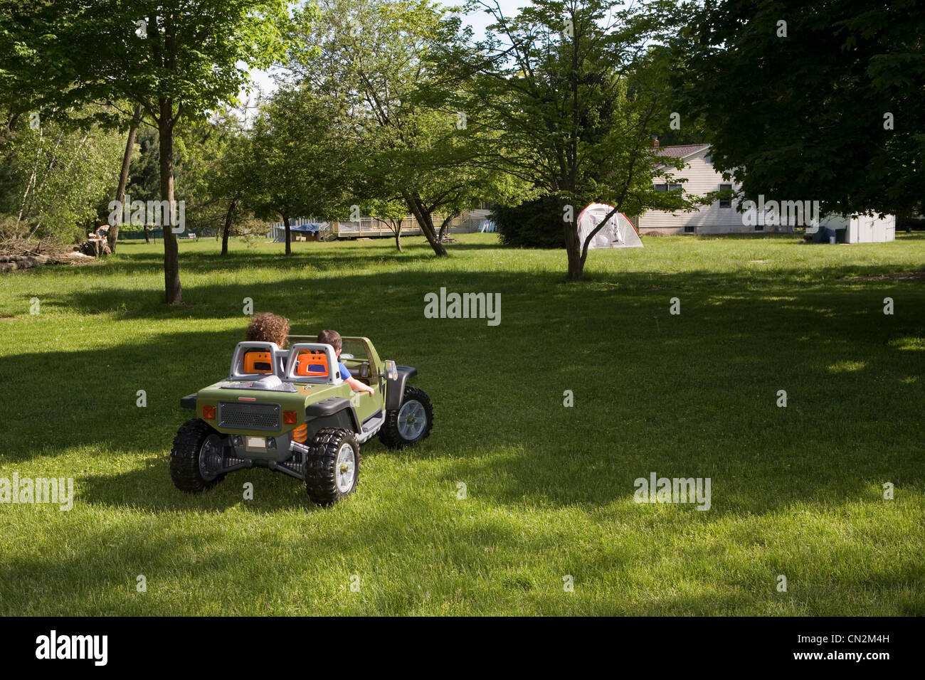 Two children driving toy car in garden Stock Photo - Alamy