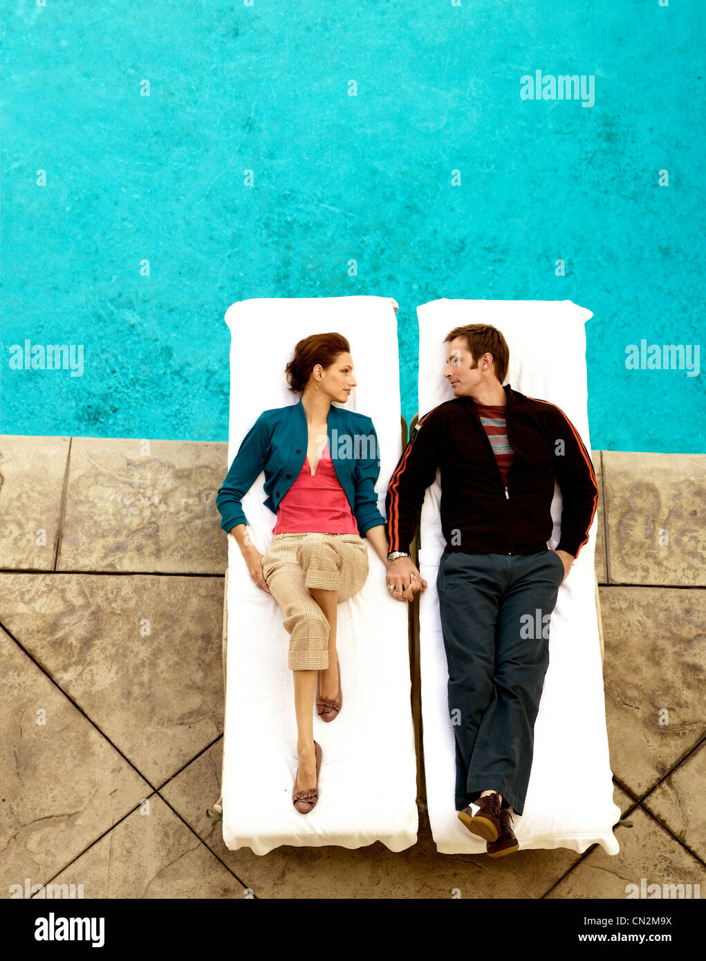 Couple lying on lounge chairs at poolside Stock Photo - Alamy