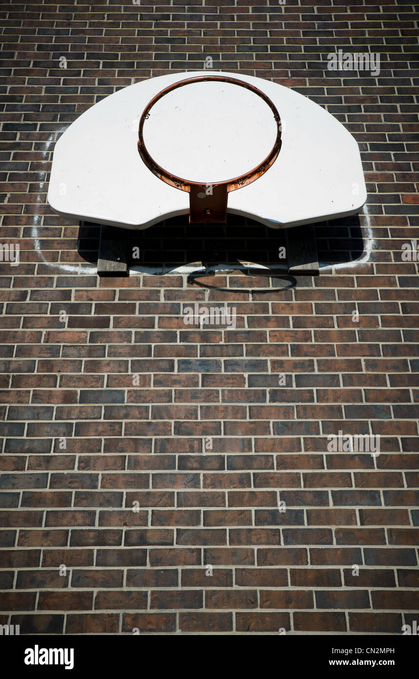 Looking up at a netless, rusty basketball hoop affixed to an inner-city ...