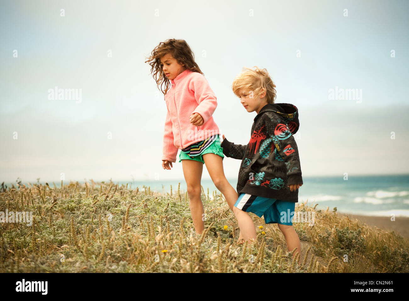 Two children walking along coast Stock Photo - Alamy