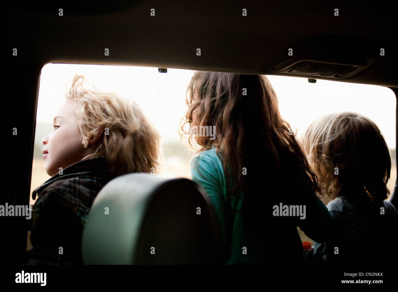 Three children looking through car window Stock Photo - Alamy
