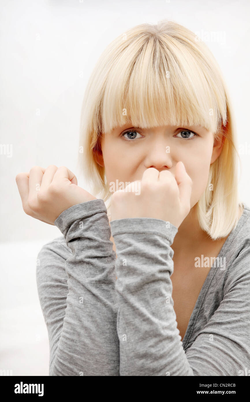 Stressed young woman eating her nails at home Stock Photo - Alamy