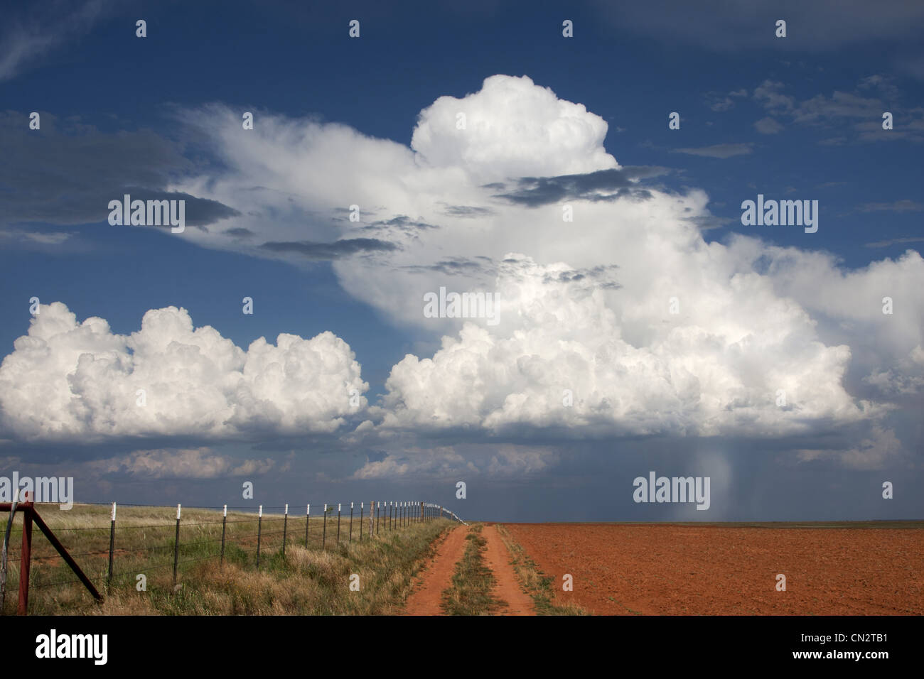 Fence Separating Plowed and Unplowed Fields Against Blue Sky and White ...