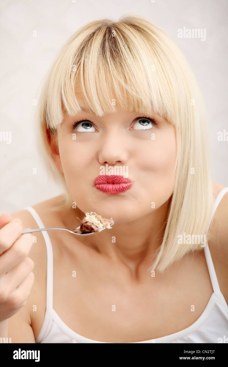 Beautiful woman's eating cake. In home Stock Photo - Alamy