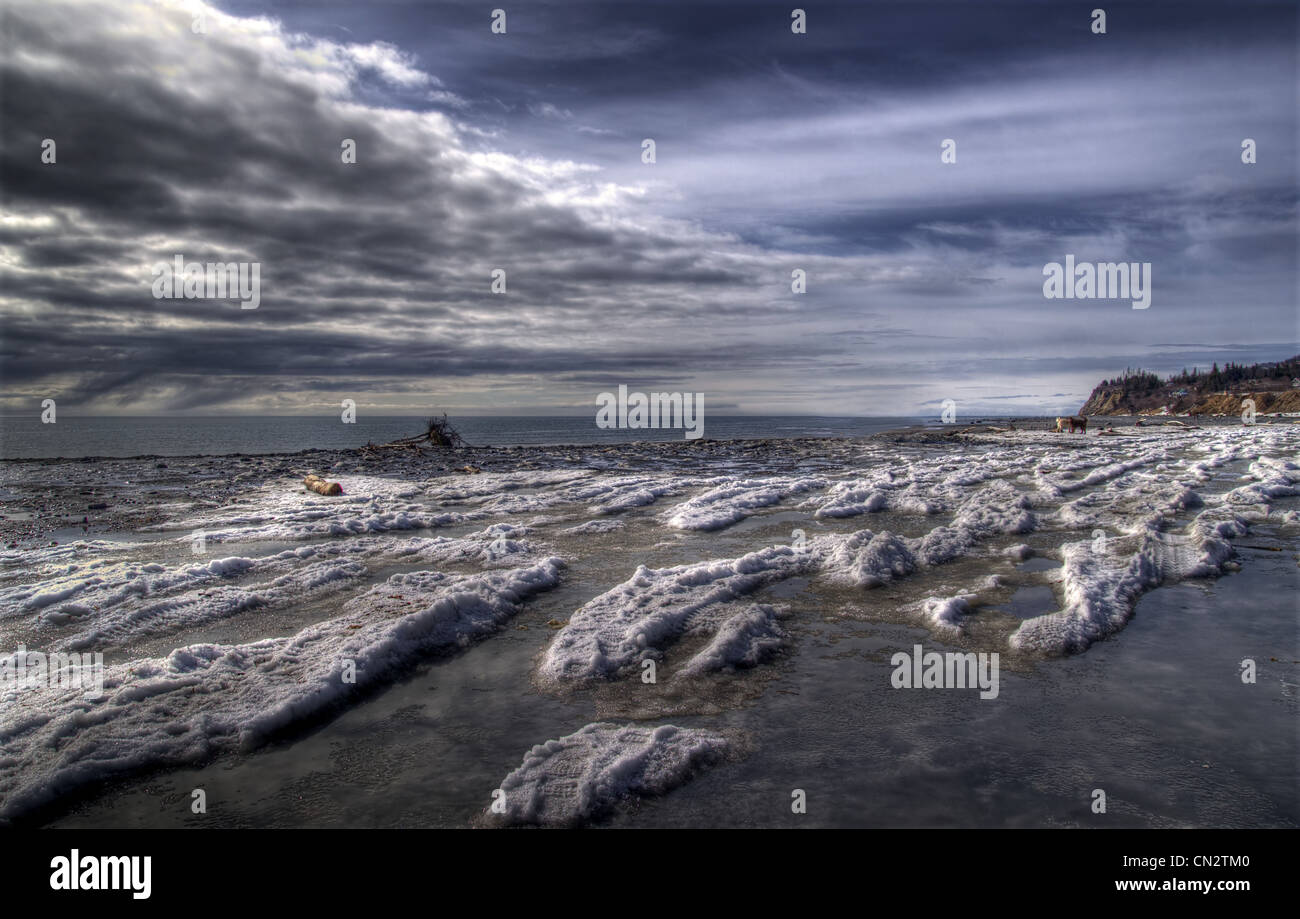 Patterns in melting snow on an Alaska beach with a storm cloud and some ...
