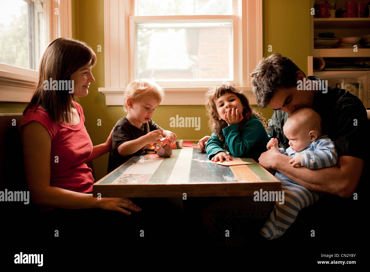 Family sitting at kitchen table Stock Photo - Alamy